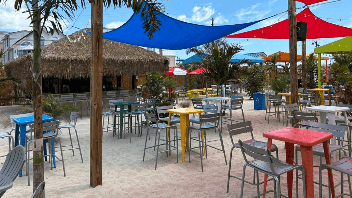 Outdoor beachside seating area with colorful shade sails and metal ...