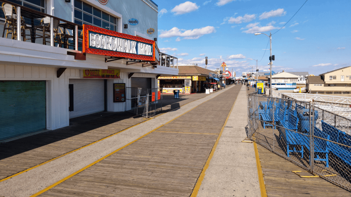 Empty wooden boardwalk along a row of closed shops on a sunny day ...