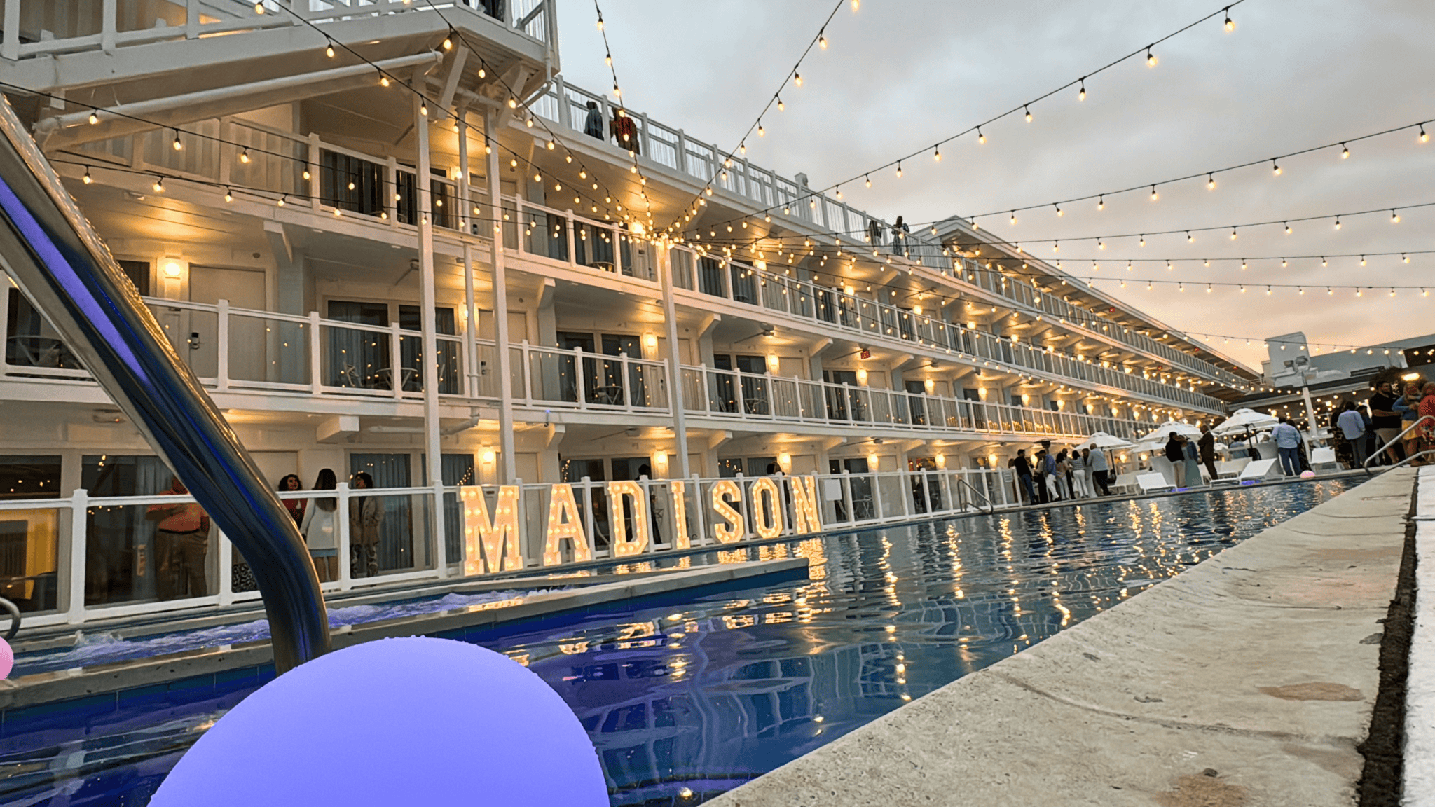 A lit-up Madison sign by a swimming pool at dusk. - Wildwood Video Archive