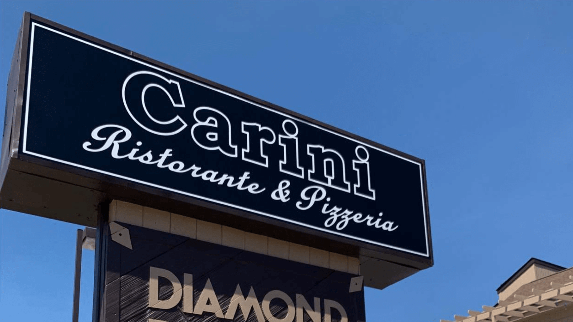 Signboard of Carini Ristorante & Pizzeria against a clear blue sky ...