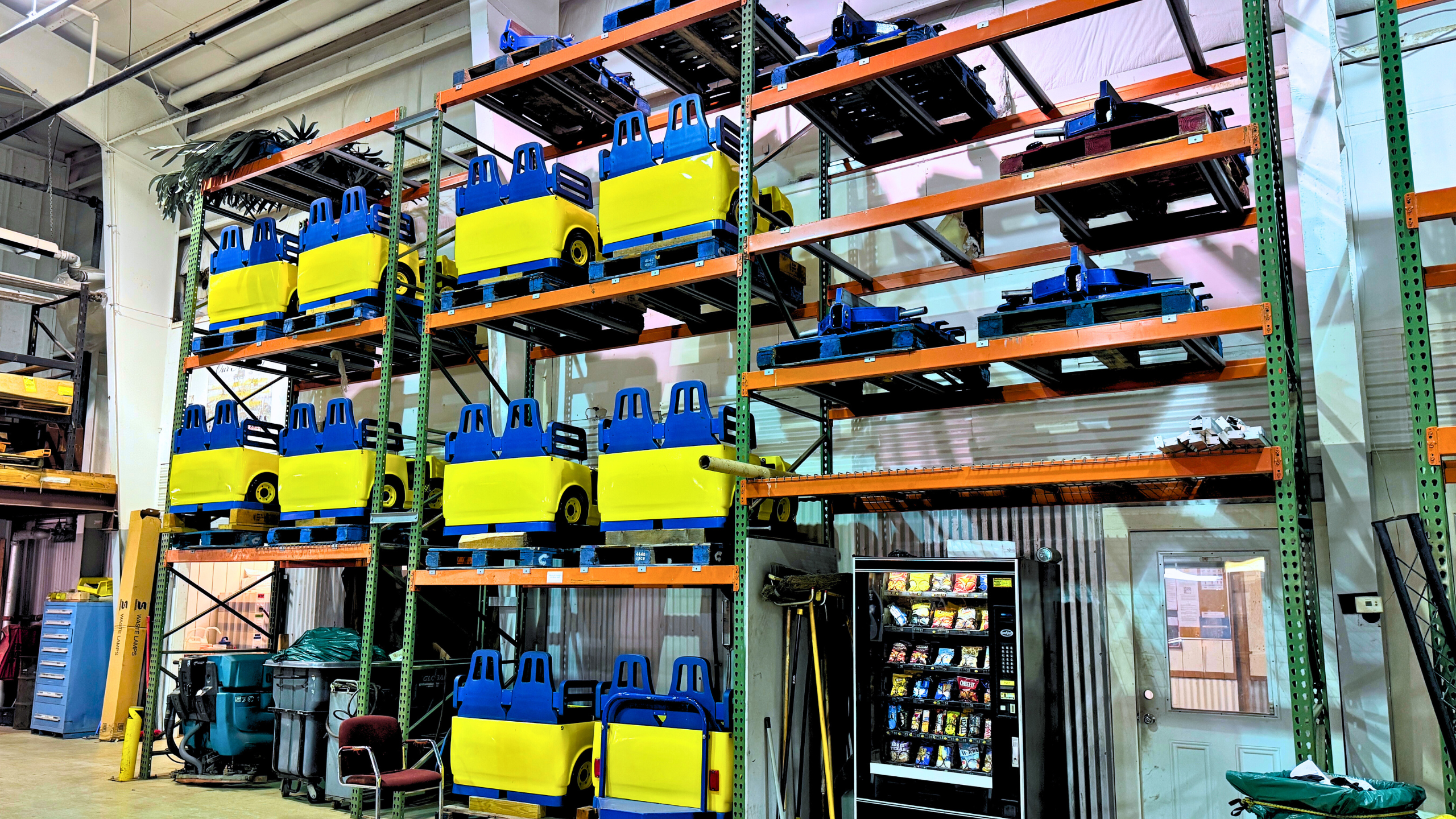 Yellow and blue carts stored on metal shelves in a warehouse ...