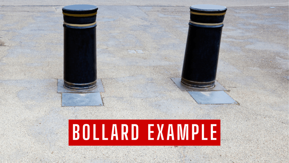 Two black bollards on a concrete surface with a red label. - Wildwood Video Archive